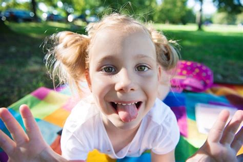 Premium Photo Portrait Of Girl Teasing While Sitting At Park
