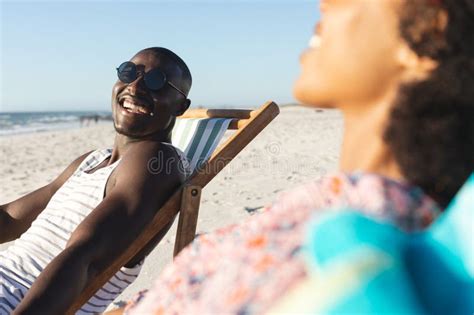 Happy African American Couple In Sunglasses Sitting In Deckchairs