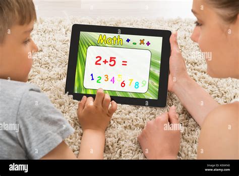 Close Up Of Mother And Son Solving Math Problem On Digital Tablet At