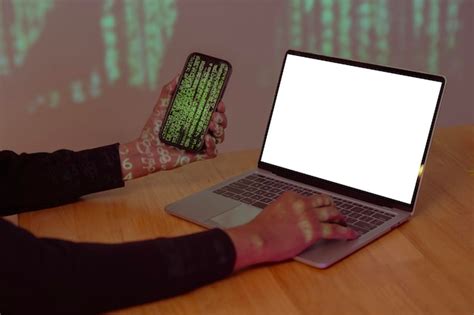 Premium Photo Cropped Shot Of Hacker Hands Holding A Mobile Phone And Stealing Data Using