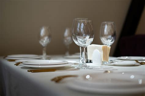 세련되고 우아한 골드 도금 된 칼과 흰색 접시 빈 접시가있는 테이블 세팅 창에서 빛에 안경 측면 보기입니다 저녁 식사에 대한