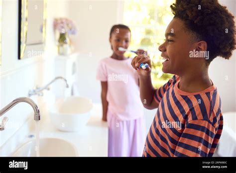 Brother And Sister In Bathroom At Home Brushing Teeth Together Stock