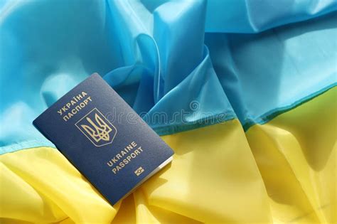 One Ukrainian Biometrical Passport On Folded Waving Flag Of Ukraine