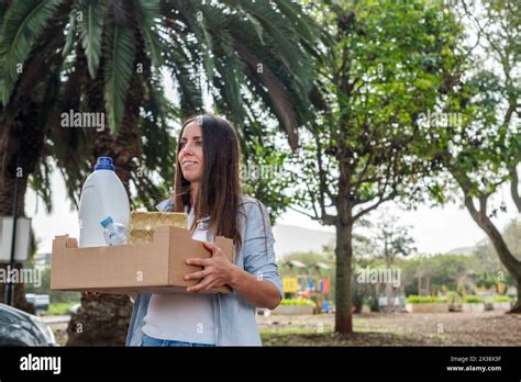 A Woman Holds A Cardboard Box With Garbage To Recycle And Throw In The