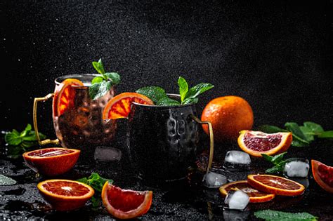 라임 블러드 오렌지 생강 맥주 보드카 및 민트와 함께 구리 컵에 튀는 모스크바 노새 칵테일 동결 모션 0명에 대한 스톡 사진 및