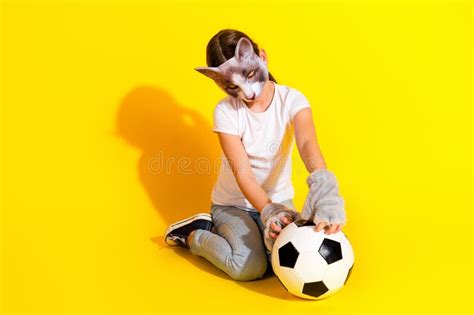 Young Girl In A Cat Mask Sitting With A Soccer Ball Against A Vibrant