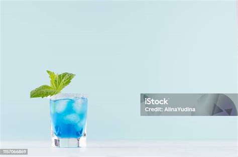 파스텔 민트 배경에 우아한 샷 유리에 얼음 조각 소금 테두리 녹색 민트와 여름 차가운 블루 라군 음료 0명에 대한 스톡 사진 및