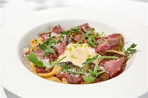 파스타 라미와 치즈와 크림 소스를 곁들인 수제 파스타 흰 테이블에 쇠고기와 소스를 곁들인 이탈리아 파파델 햇볕의 그림자가있는 여름 식사 이탈리아 음식 로스트 비프에 대한