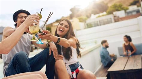 Jóvenes felices brindando cócteles en una fiesta en la azotea jóvenes amigos pasando el rato y