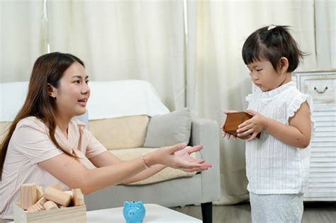 아시아 교사는 유치원에 들어가기 전에 아이들을 가르칩니다 아이가 나무 장난감을 선생님에게 건네며 협력과 공유를 배웁니다 대화형 놀이 시간은 의사 소통과 사회적 발달을