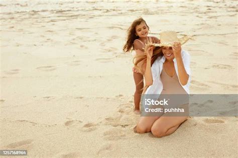 해변에서 아이와 어머니 엄마의 머리에 밀짚 모자를 넣어 수영복에 무두질 어린 소녀 젊은 여자와 그녀의 딸은 여름 주말에 재미를