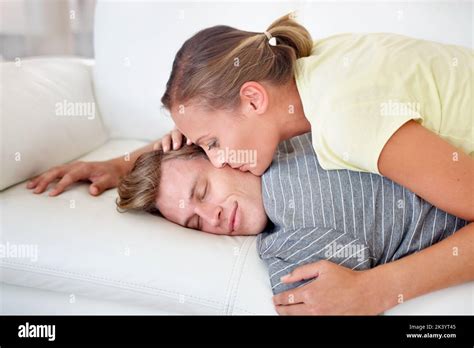 My Sleeping Prince A Woman Leaning Over And Kissing Her Boyfriend Lying On A Sofa Stock Photo