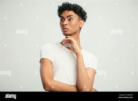 Portrait Of A Young Man Standing With His Hand On Chin And Looking Away