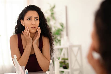 불행한 밀레니엄 세대 여성이 거울에 비친 자신의 반사를보고 욕실에서 첫 번째 주름을 확인하고 공간을 복사합니다 30 34세에