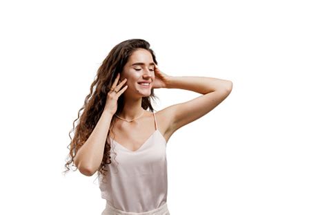 맑은 피부와 긴 물결 모양의 머리를 가진 매력적인 소녀 곱슬 헤어 스타일을 가진 갈색 머리 젊은 여자가 그녀의 얼굴을 만진다 스파 피부과 전문의 화장품 살롱 광고 갈색