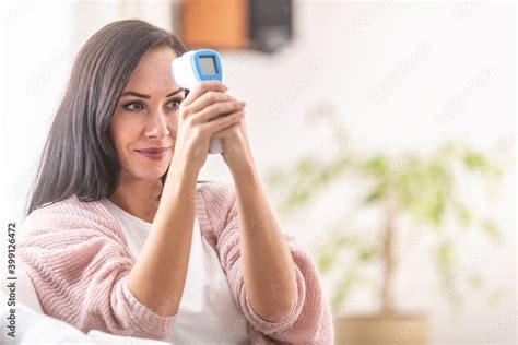 Woman Self Measuring Temperature With An Infrared Digital Thermometer On Her Forehead Stock