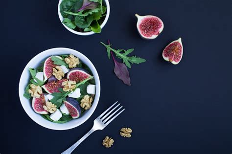 검은 배경의 흰색 그릇에 Arugula Feta 치즈 무화과 및 호두를 곁들인 샐러드 상단 보기 공간을 복사합니다 0명에 대한
