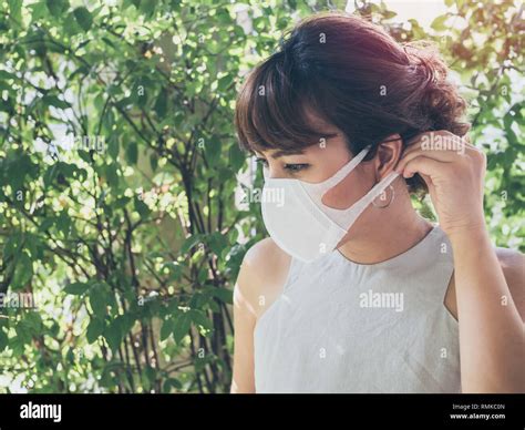 Beautiful Asian Woman Wearing White Protective N95 Dust Mask On Green