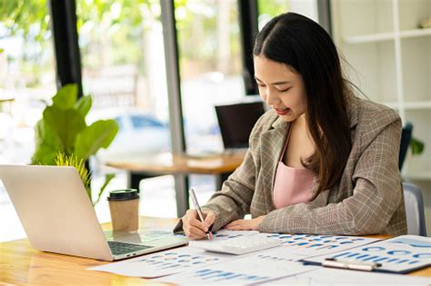 노트북 컴퓨터로 일하는 아시아 사업가 계산 분석 젊은 여성 재정 고문 통계 보고서 준비 문서 연구 사무실에서 재무 차트 확인 계산함에 대한 스톡 사진 및 기타 이미지