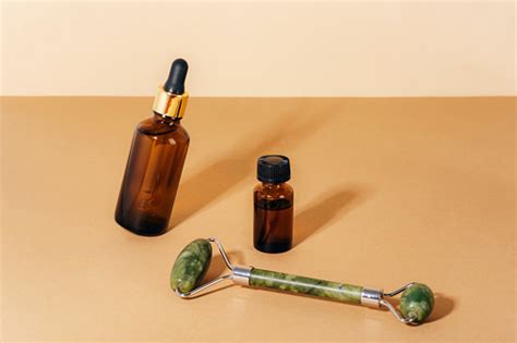 갈색 화장품 세럼 병 에센셜 오일 옥 페이셜 롤러가 중성적인 베이지색 배경에 있다 천연 스킨 케어 화장품 개념 모형 복사 공간