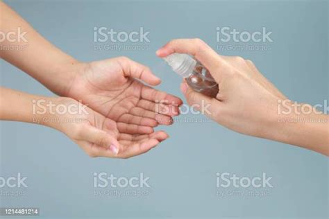 회색 배경을 통해 작은 아이의 손에 알코올 스프레이 손 소독제를 적용 성인 2명에 대한 스톡 사진 및 기타 이미지 2명