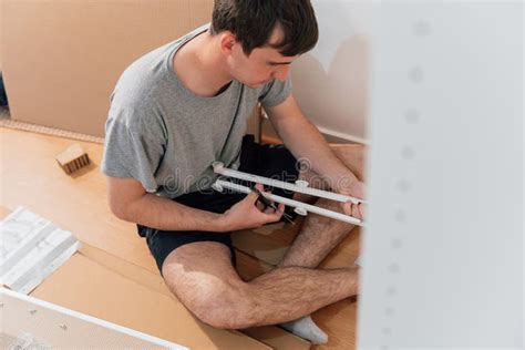 Young Man Assembling A Closet In The Bedroom Of His House Sitting On