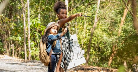 다양성의 그룹 여름 화창한 날에 숲 산에서 함께 배낭 하이킹을 하는 어린 소녀 친구들 세 아이가 앉아서 숲을 탐험하는 지도를