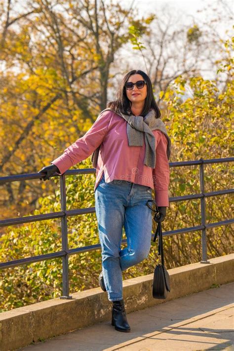 Pretty Woman With Dark Hair Wearing Pink Sweater Jeans Sunglasses