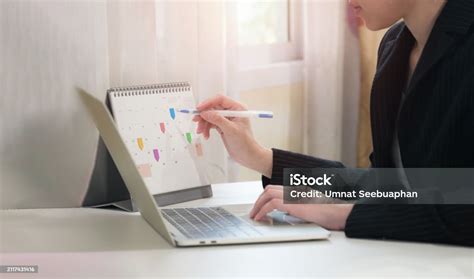 2024년 이벤트 플래너 캘린더 의제 시간표 사무실에 있는 책상에서 전화기로 플래너를 확인하고 책상 달력에 메모를 하는 사업가