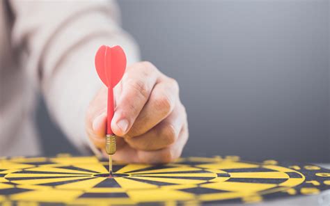 노란 다트판의 과녁에 빨간 다트를 정확하게 놓는 사업가의 손 이 이미지는 초점 정확성 및 전략적 정확성으로 목표 달성을 상징합니다 결심에 대한 스톡 사진 및 기타 이미지