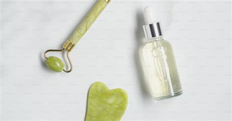 천연 노화 방지 옥 돌 에센셜 오일 스포이드 병 및 대리석 테이블에 녹색 잎이 있는 옥 롤러 얼굴 피부 관리 개념입니다 플랫 레이 평면도 사진 Unsplash의