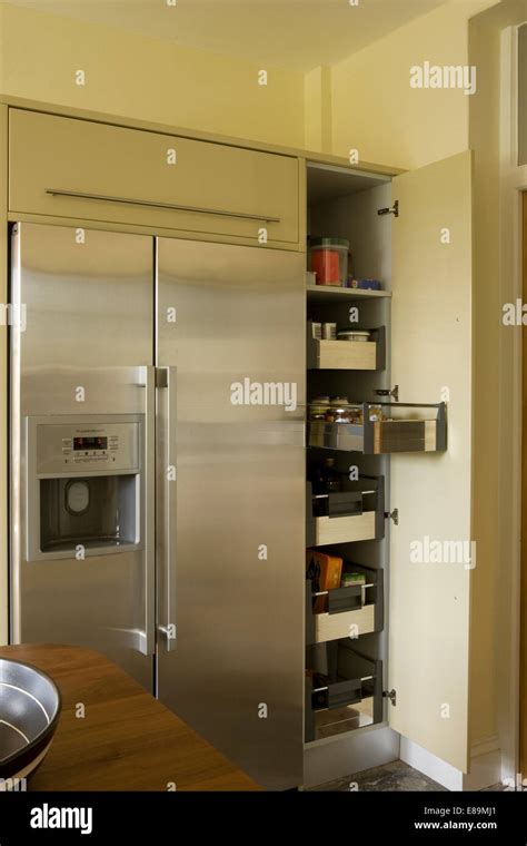 Stainless Steel American Style Fridge Beside Open Larder Cupboard In