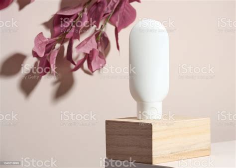 화장품을 위한 빈 흰색 플라스틱 튜브는 그림자가 있는 베이지 색 배경의 나무 연단에 서 있습니다 크림 샴푸 액체 물질용 용기 0
