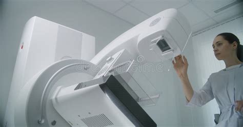 Female Doctor Uses Computer Then Sets Up Mammogram Machine For Patient