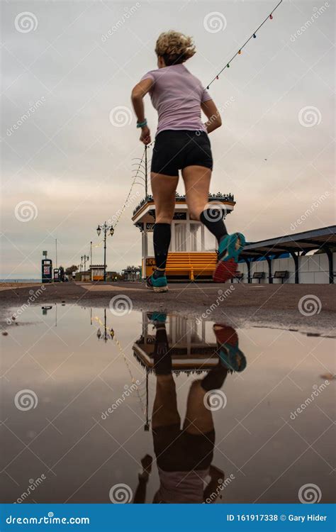 A Runner Passing A Puddle While Running At The Beach Editorial Stock