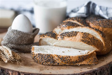 양귀비 씨를 가진 고전적인 밀 끈목 맛있는 빵 클로즈업 나무 판에 황금 빵 껍질을 곁들인 갓 구운 사워도우 빵 맛있는 빵이있는 빵집의 맥락 제과 제품 0명에 대한 스톡 사진
