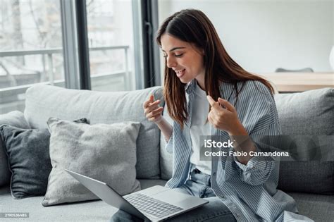 웃는 소녀는 집에서 소파에 앉아서 노트북에서 화상 통화를하는 친구나 가족과 손을 흔들며 이야기하고 행복한 젊은 여자는 인사하고 인사하고 말하고 컴퓨터에서 데이트 온라인 응용