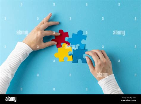 Composition Of Hands Putting Jigsaw Puzzle Pieces Together On Blue