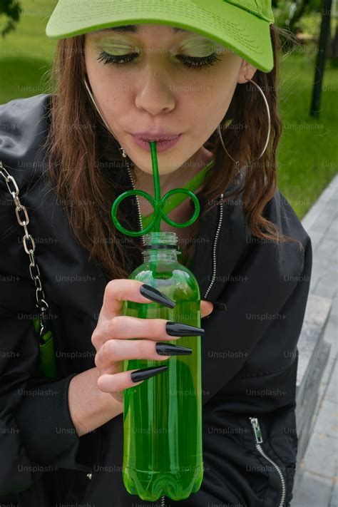 초록색 모자를 쓴 여자가 초록색 병에 담긴 물을 마시고 있다 사진 Unsplash의 브랫 그린 이미지