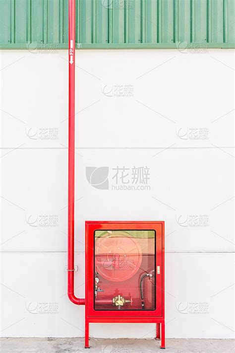白色墙壁上有红色的消防水龙带柜和灭火器