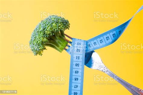 파란색 측정 테이프 노란색 배경 복사 공간 슬리밍 개념 체중 감량 및 다이어트에 싸여 포크에 신선한 녹색 브로콜리 건강한