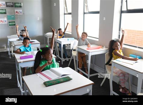 Smiling Multiracial Elementary School Students With Hands Raised