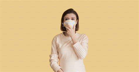 백인 임산부는 노란색 스튜디오 벽에 포즈를 취하는 의료 마스크를 쓰고 있다 사진 Unsplash의 임신한 이미지