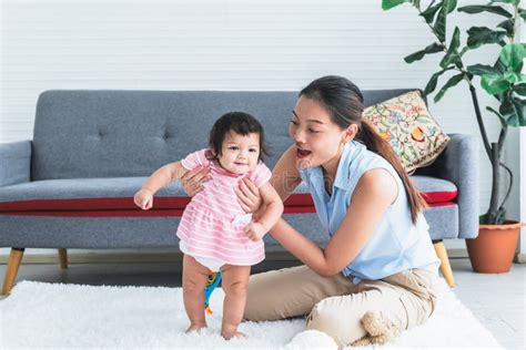 Asian Mother Smiling And Happy As She Supports Her 7 Month Old Daughter