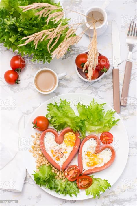 로맨틱한 아침 식사 식탁에 있는 접시에 하트 모양의 소시지 양상추 체리 토마토에 계란 튀김 위쪽 및 수직 뷰 밸런타인데이에 대한