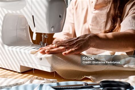 작은 스튜디오의 재봉틀에 린넨 원단을 재봉하는 재봉사 패션 아틀리에 재봉 수제 옷 개념 슬로우 패션 의식적인 소비 가위에 대한
