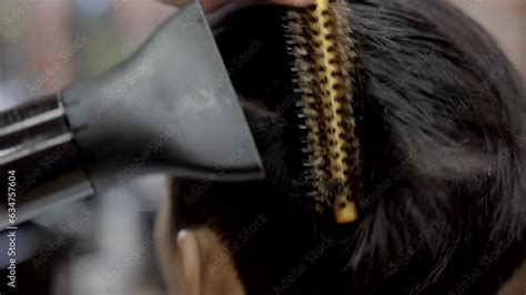 롤빗과 헤어 드라이기로 손님의 머리를 스타일링하는 헤어디자이너 Stock ビデオ Adobe Stock