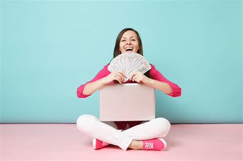 전체 길이 장미 셔츠 블라우스에 젊은 여자의 초상화 바닥에 앉아 흰 바지 핑크 블루 파스텔 벽 배경 스튜디오에 고립 된 돈을