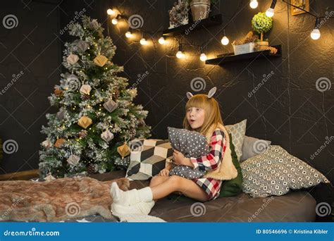 Маленькая девочка сидит на кровати и смотрит везде во времени рождества Стоковое Фото