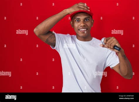 Young Hispanic Man Singing Song Using Microphone Stressed And
